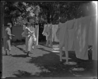 Two unidentified women hanging laundry on a clothesline at the Gettle ...