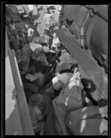 Rescuers try to access a car wedged between 2 train cars, [between 1920 ...