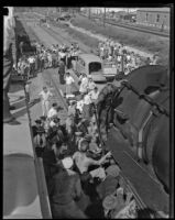 Rescuers work to remove a car wedged between 2 train cars as spectators ...