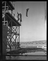 Marines jump off of a platform and into a debris-strewn pool during ...