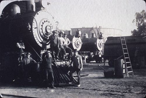 A crew of railroad men posing in front of steam locomotives in Beaumont ...