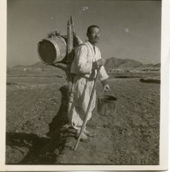 Man carrying a barrel with an A-frame back carrier — Calisphere