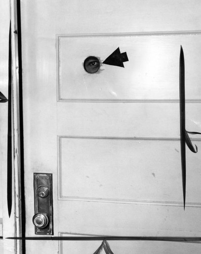 Eye looking out through peephole of barred door during Highland Park ...