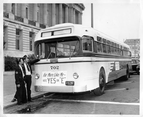 [Muni bus with sign on it reading "For More Like Me - Vote YES on E ...