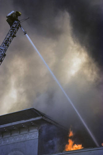 Firefighter on top of a ladder battling a blaze at Thrifty Drug Store ...