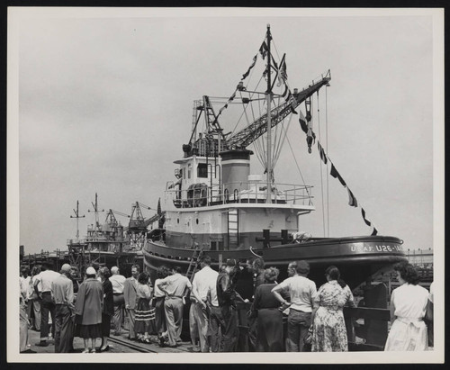 Crowd stands on dock by tugboat — Calisphere
