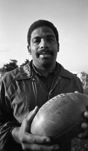 Coach Glenn Bell posing with a football, Los Angeles, 1982 — Calisphere