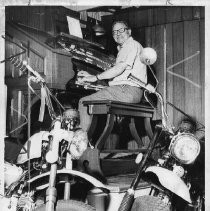Joe Coon sits at his organ surrounded by motorcycles — Calisphere