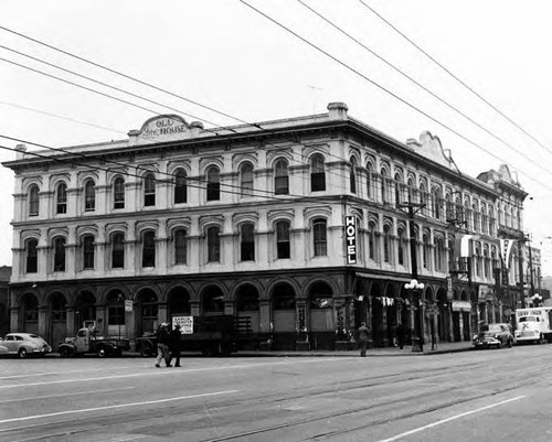 Corner view of Pico House, named "Old Pico House" with cars and trucks ...