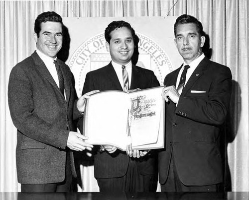 Los Amigos: Three men holding Pan American week booklet — Calisphere