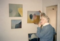Ann O'Hanlon reviewing hanging of paintings, circa 1990 — Calisphere