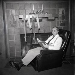 Reading by the fireplace with stockings — Calisphere