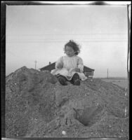 Elizabeth West sits on a pile of sand, Venice, about 1905 — Calisphere