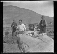Wilfrid Cline, Glen Velzy and Charles Stavnow eat supper on a rock by ...