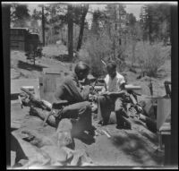 Neil Wells and H. H. West, Jr. sit in the middle of a woodpile outside ...