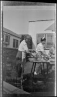 Alice Shaw and others wash dishes in the rear yard of W. H. Shaw's home ...