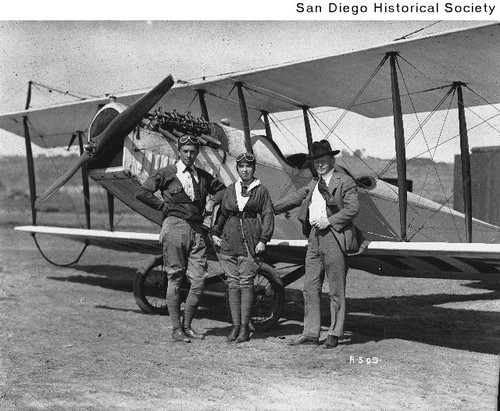Two men standing with Georgia "Tiny" Broadwick in front of a biplane ...