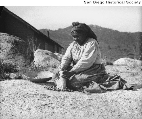A San Ygnacio Indian woman grinding acorns with a metate — Calisphere