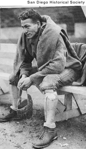 Sam Russo seated on a bench, wearing football equipment — Calisphere