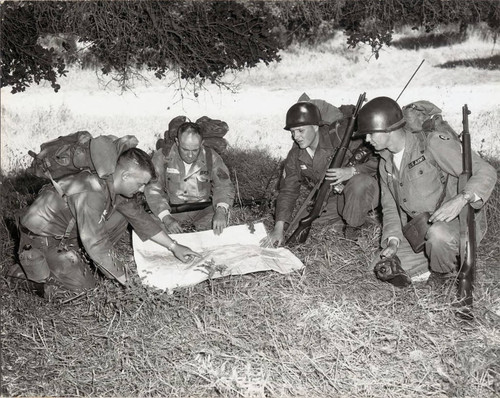 Photograph of four soldiers reading a map — Calisphere