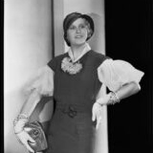 Peggy Hamilton modeling a fitted dress, a hat and embroidered gloves ...