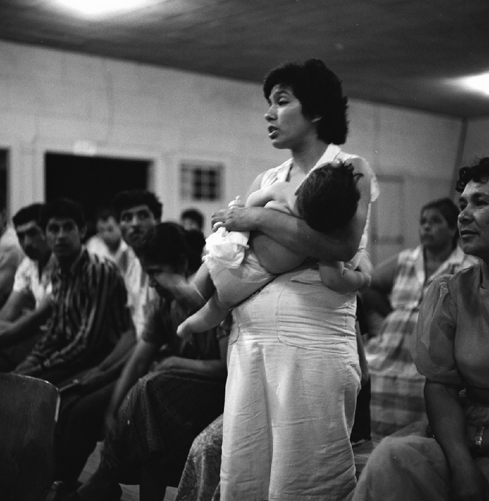 A woman with baby in arms speaks at an AWOC organizing meeting — Calisphere