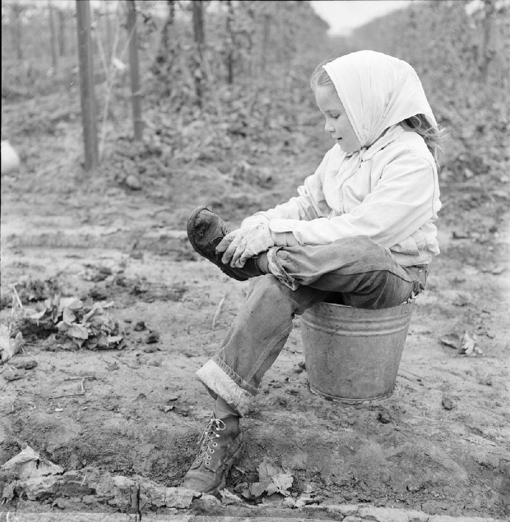 Girl sitting on bucket fixing her boot — Calisphere
