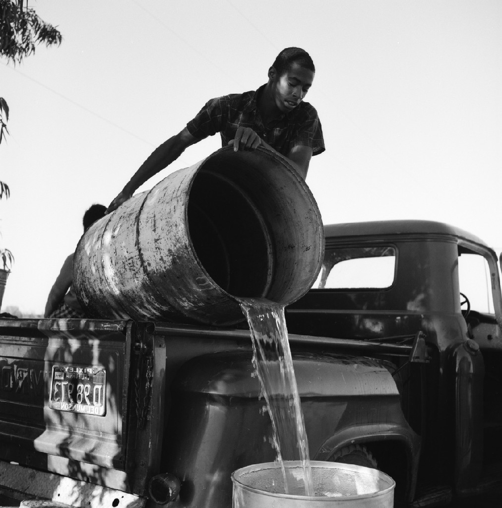 Man pouring liquid from barrel — Calisphere
